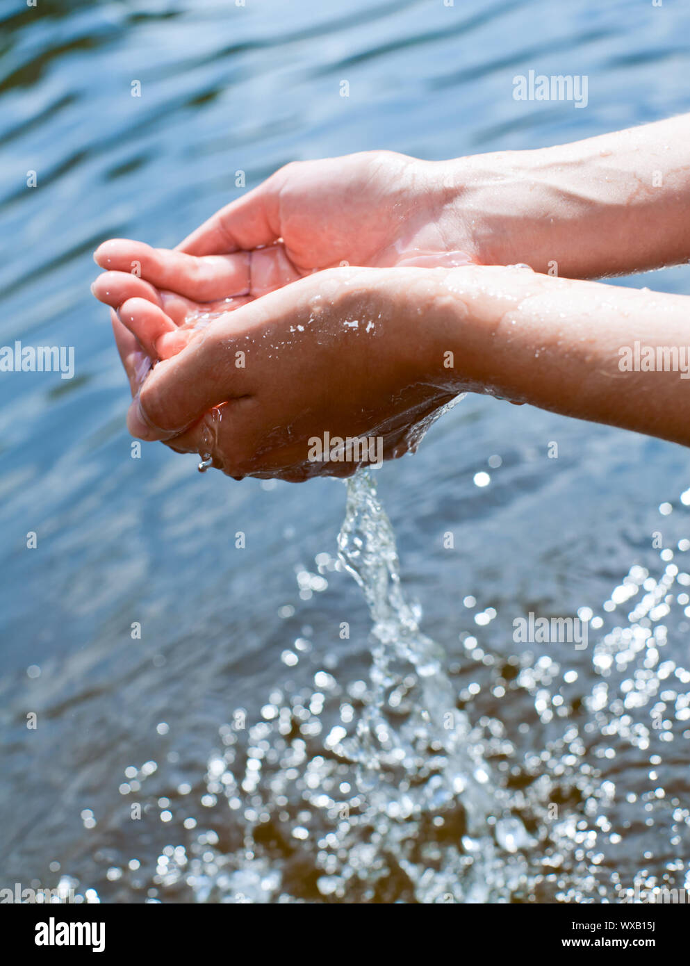 Water pouring out of a young woman's hands Stock Photo - Alamy