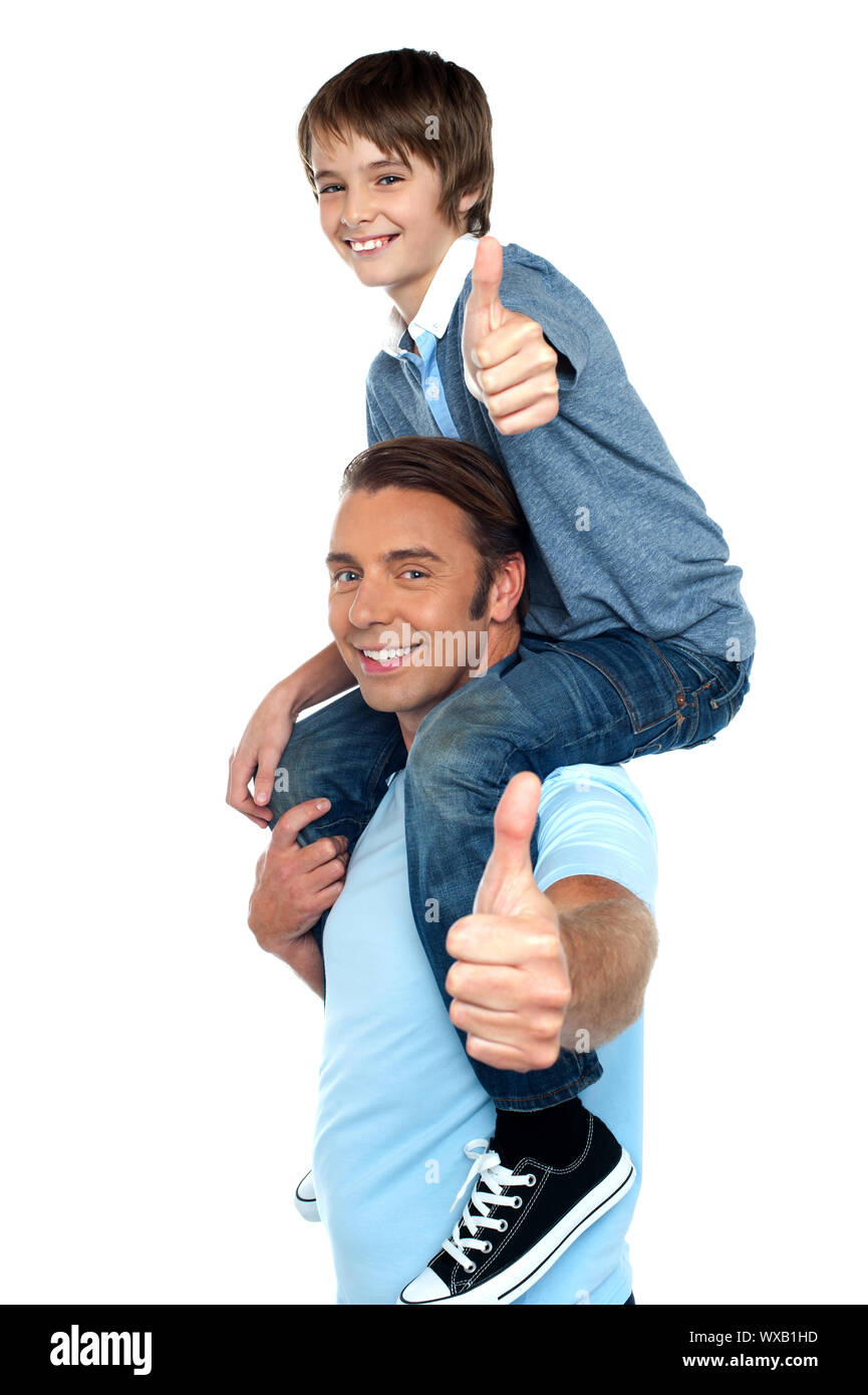 Confident father carrying his son on shoulder. Both gesturing thumbs up ...
