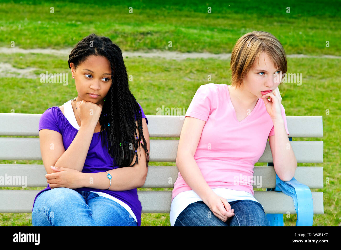 Two bored teenage girls sitting on bench Stock Photo - Alamy