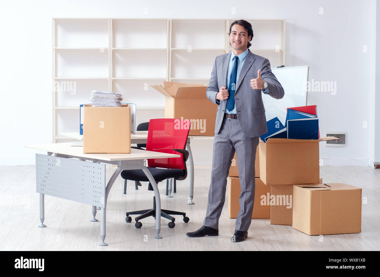 Young man employee with boxes in the office Stock Photo - Alamy