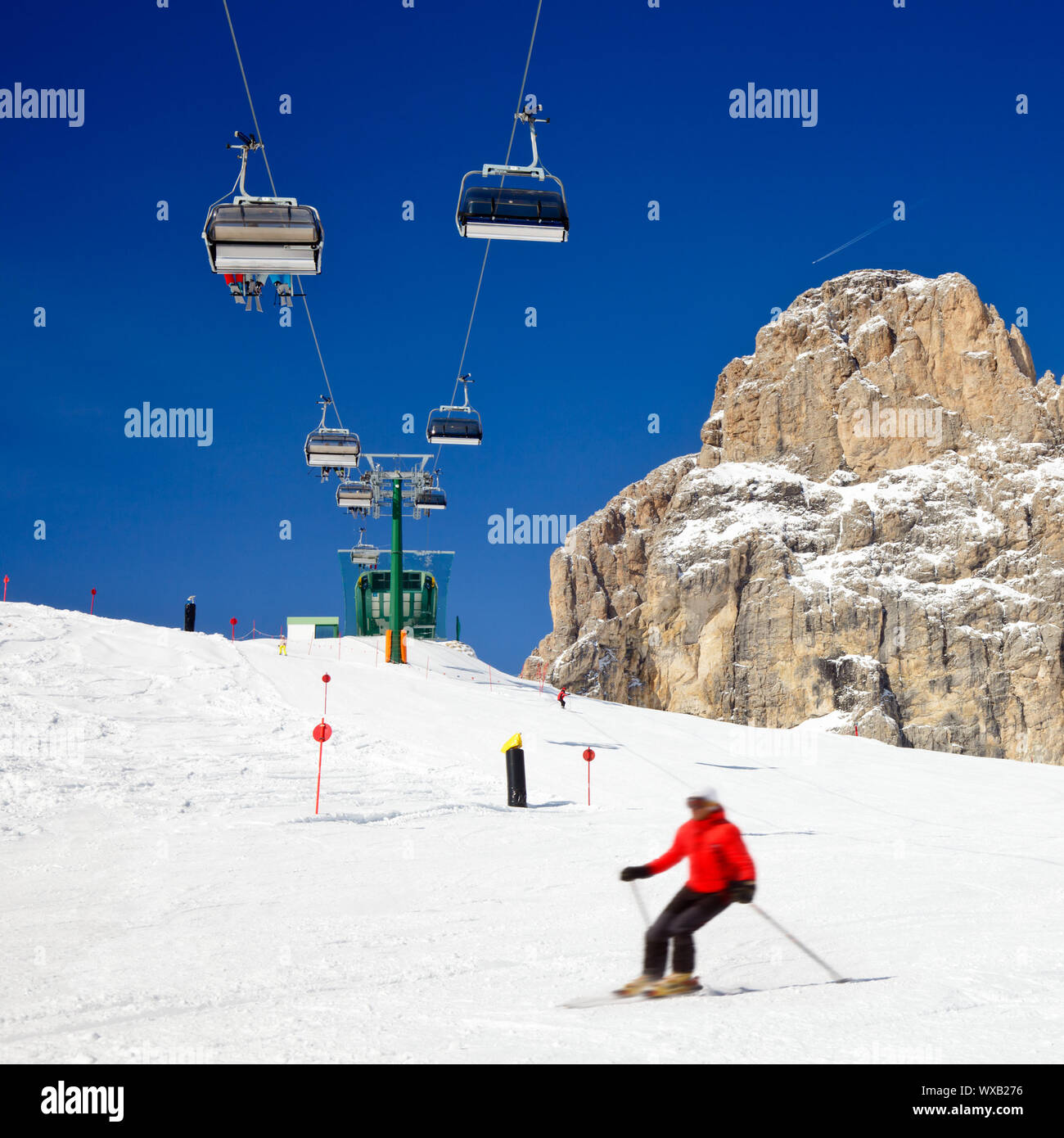 Skier going down the slope under ski lift at Sella Ronda ski route in ...