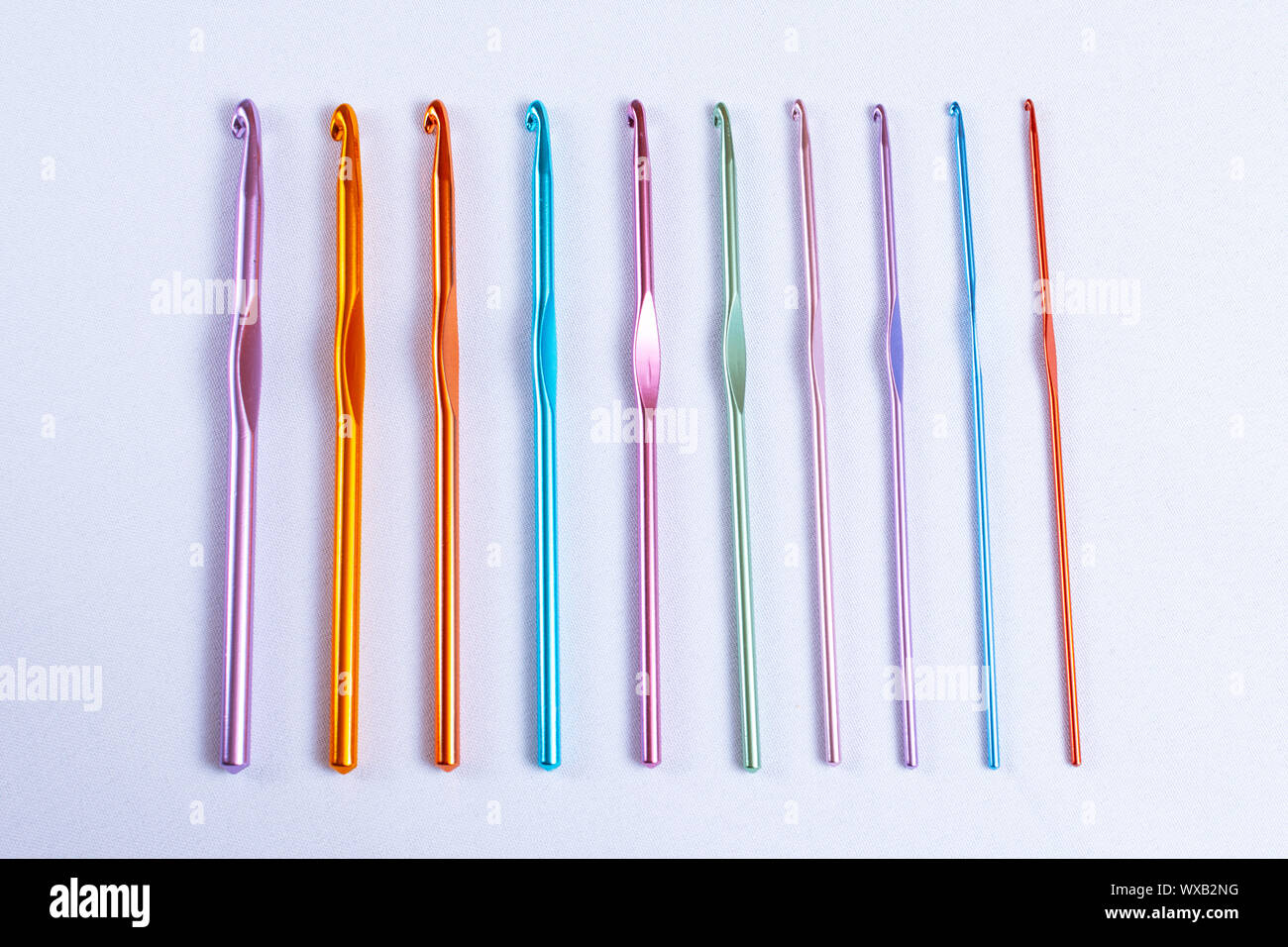 Crochet hooks of different sizes and colors arranged in one row ...