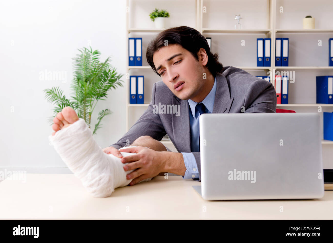 Leg injured employee working in the office Stock Photo - Alamy