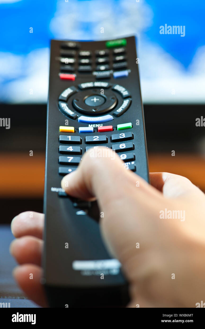 Hand holding television remote control pressing buttons Stock Photo - Alamy
