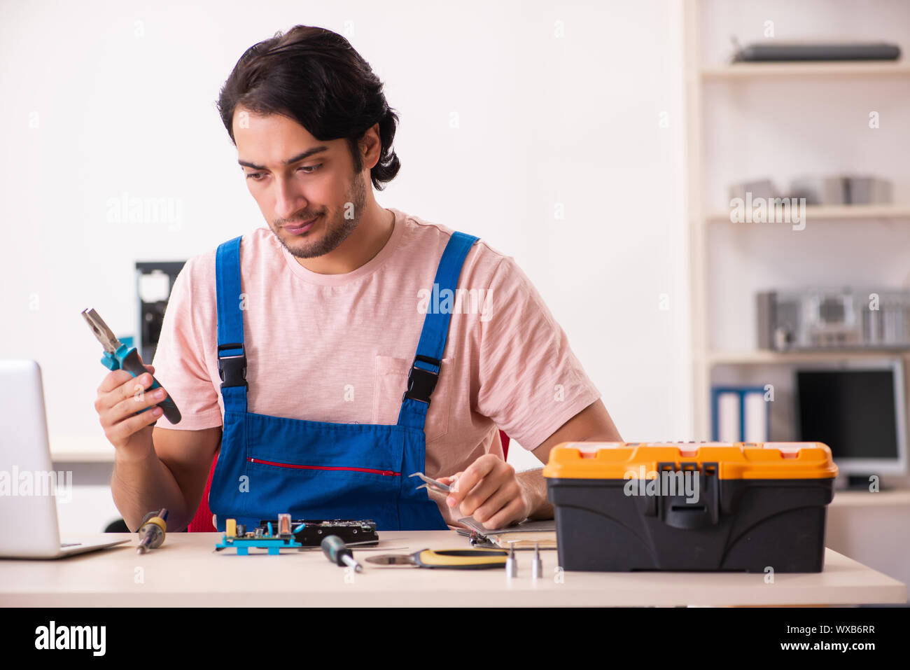Young male contractor repairing computer Stock Photo - Alamy