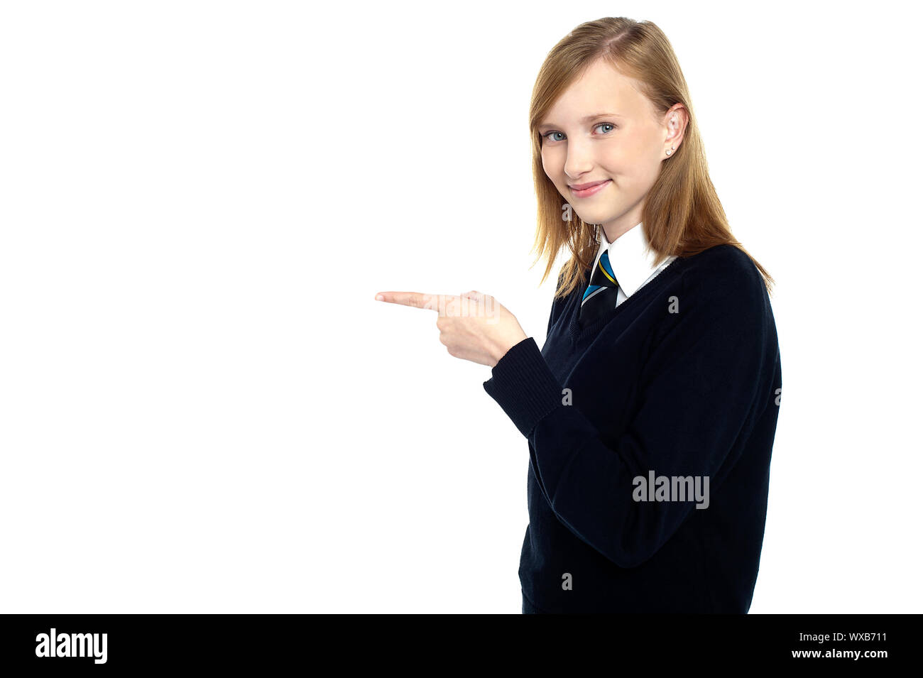Pretty schoolgirl pointing towards copy space area. Isolated over white ...