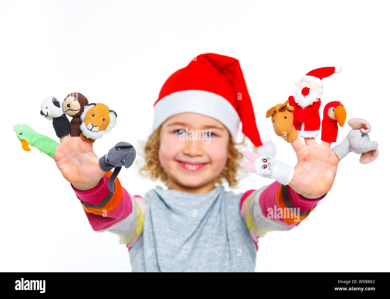 Cute and happy girl in Santa's hat playing with finger puppets ...