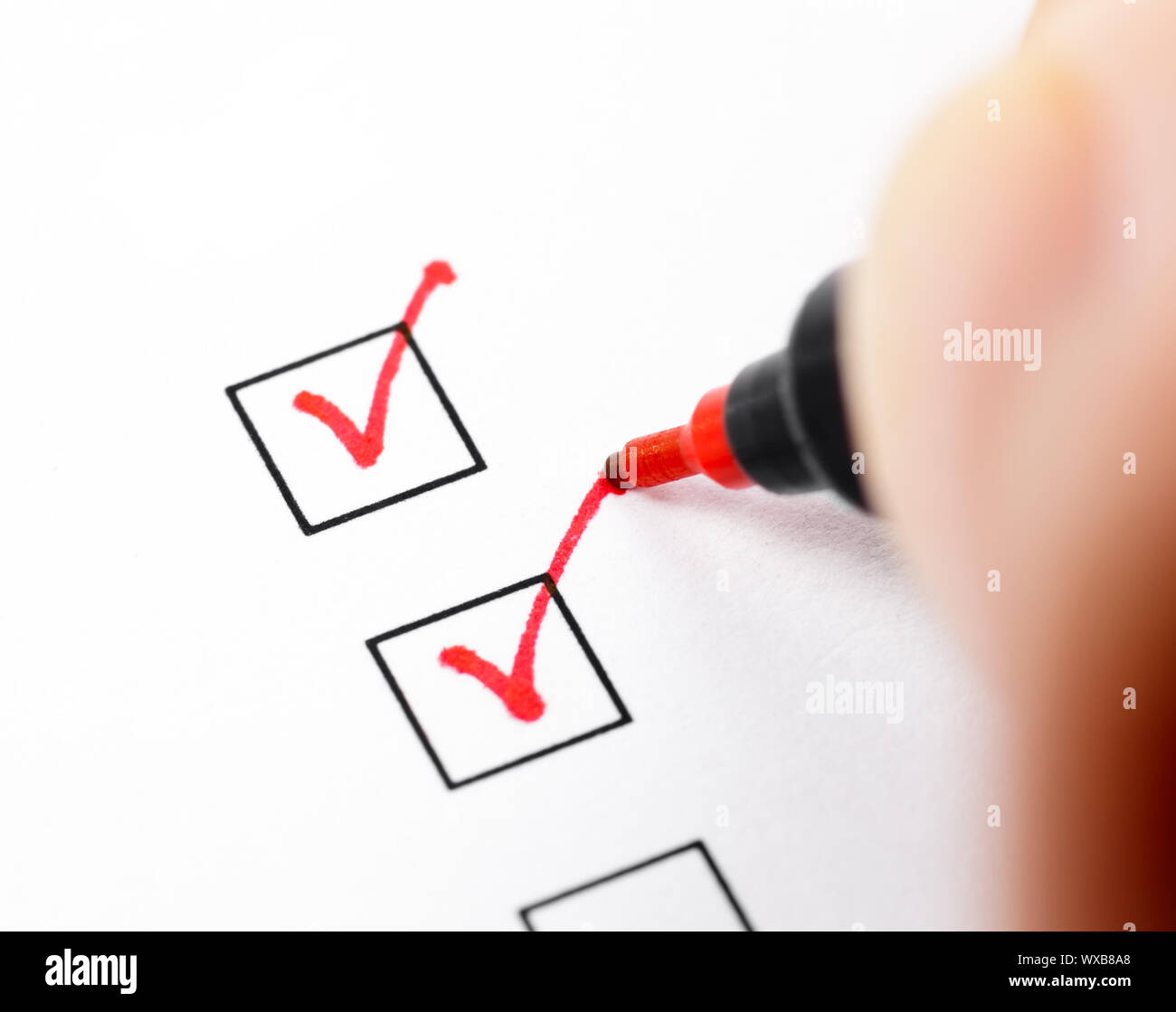 Hand with red pen marking a check box Stock Photo - Alamy