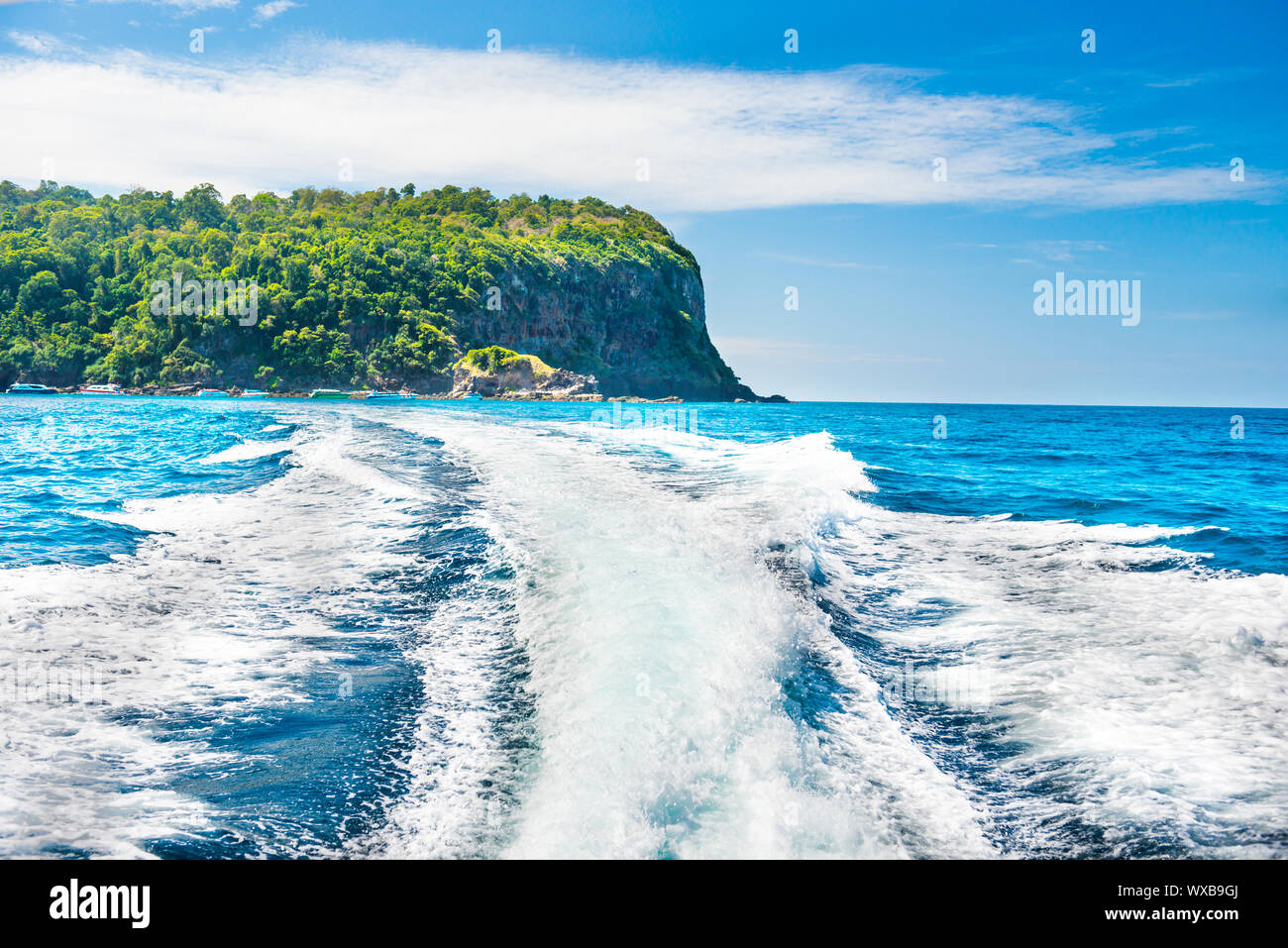 Wake of boat on water surface beside island coast Stock Photo - Alamy