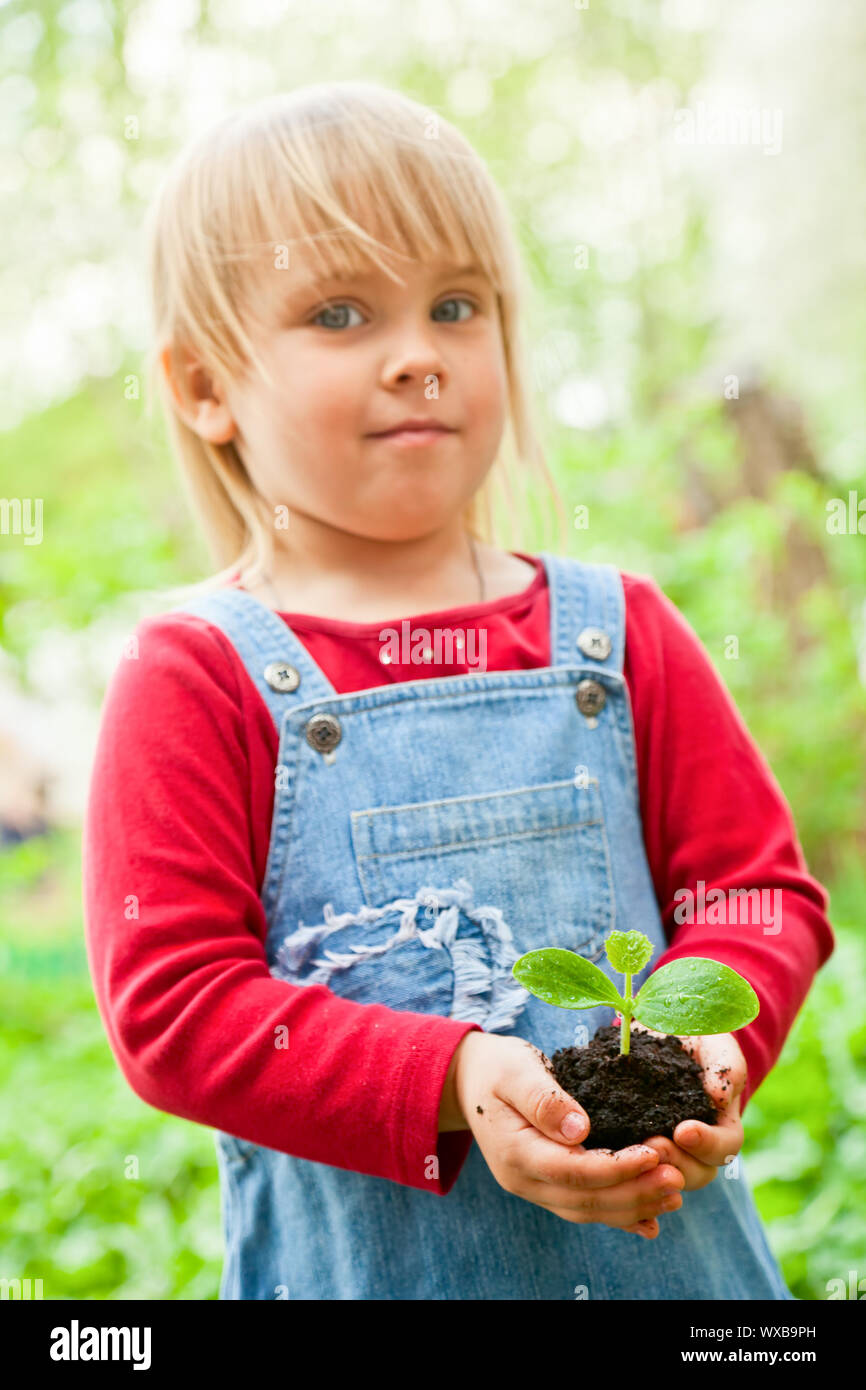 Blonde girl wearing red dress showing seeding with ground, focus on ...