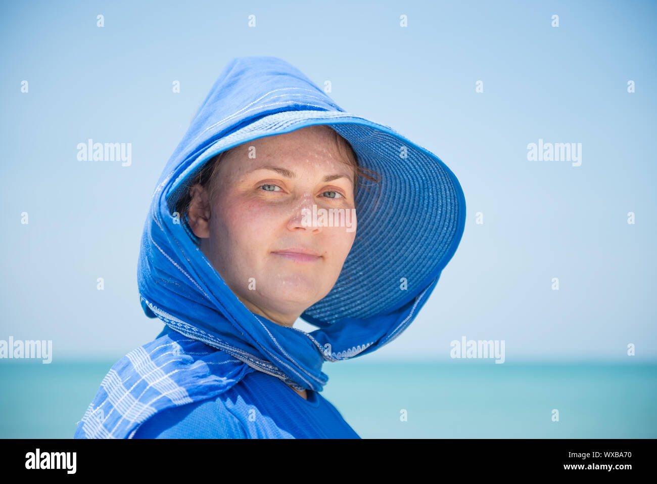 Woman in hat on blue water background Stock Photo - Alamy