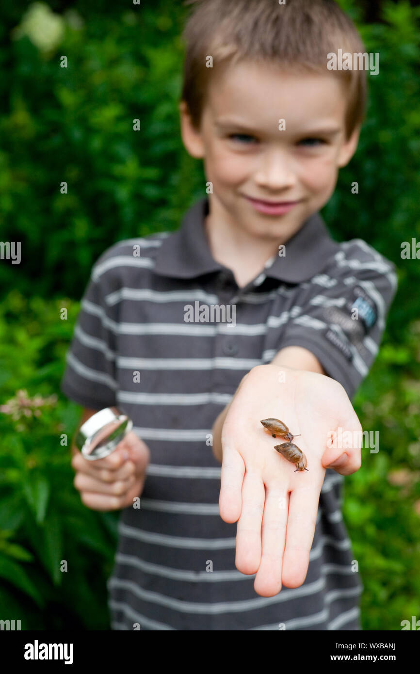 Young boy showing snails on his palm, focus on snails Stock Photo - Alamy