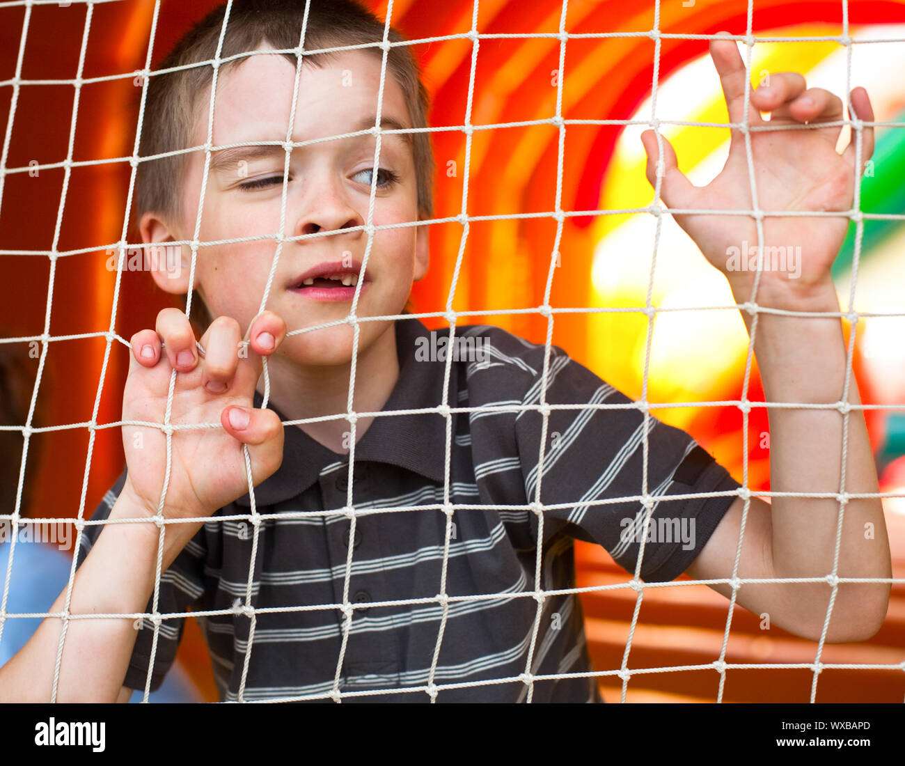 Young boy behind the net at playground Stock Photo - Alamy