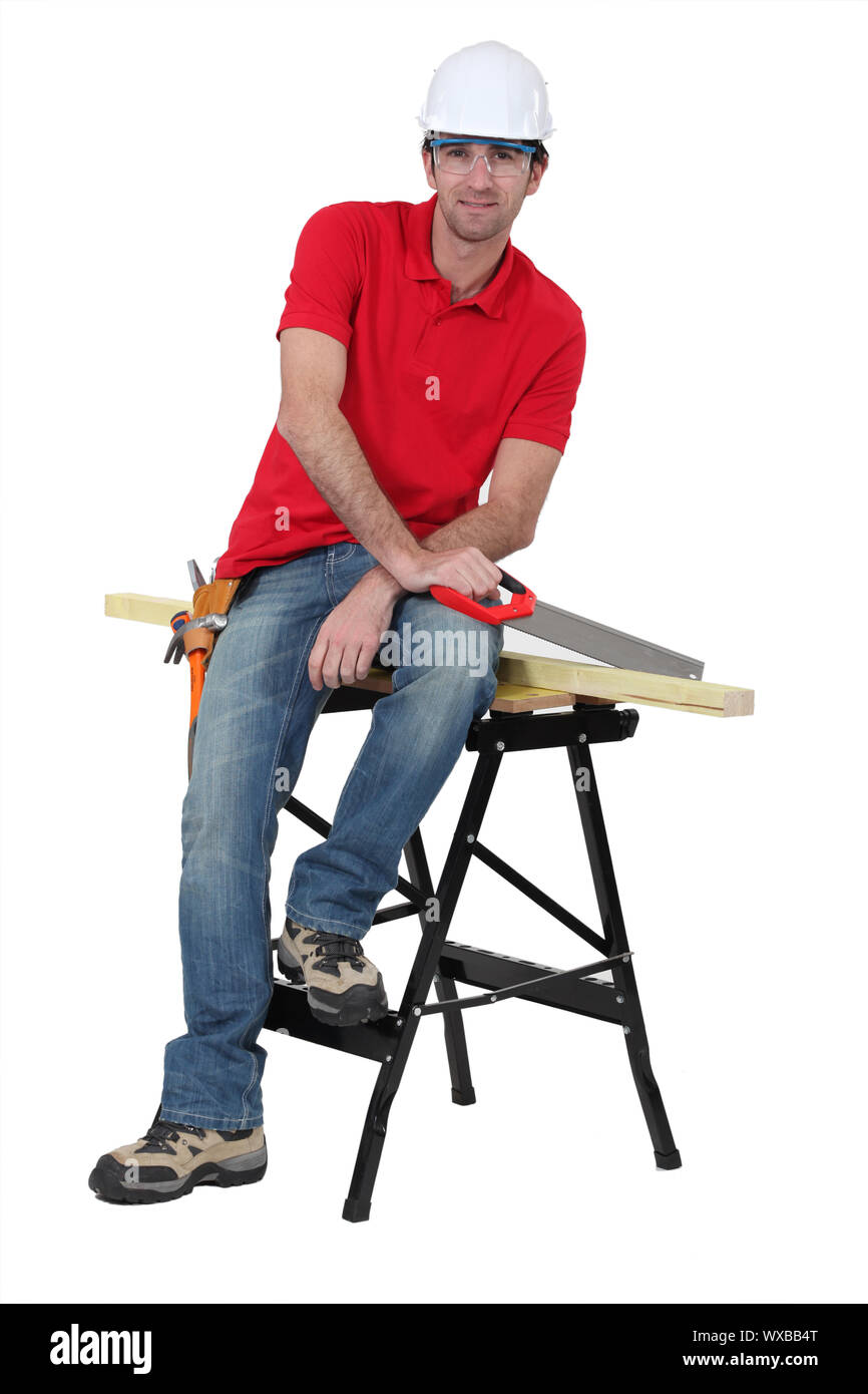 Man with a saw sitting on a workbench Stock Photo - Alamy