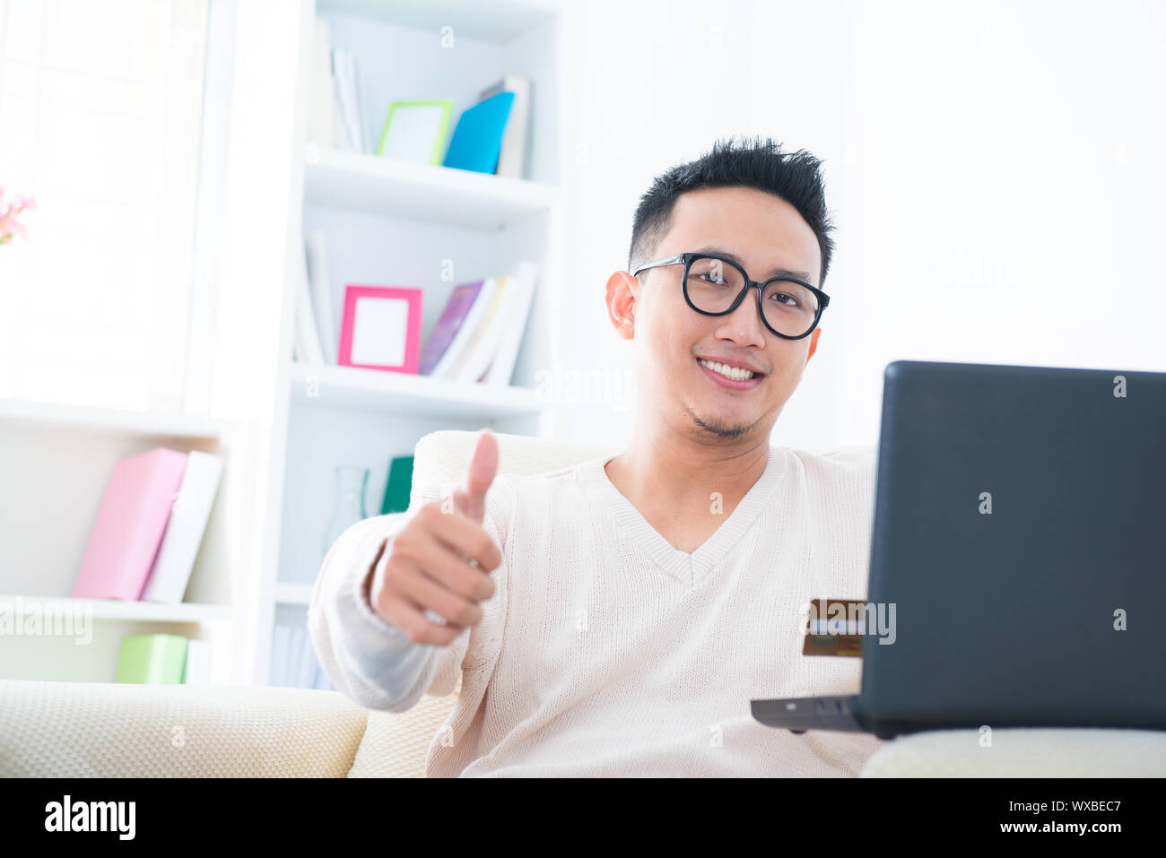 Thumb up Southeast Asian male internet shopping at home Stock Photo - Alamy