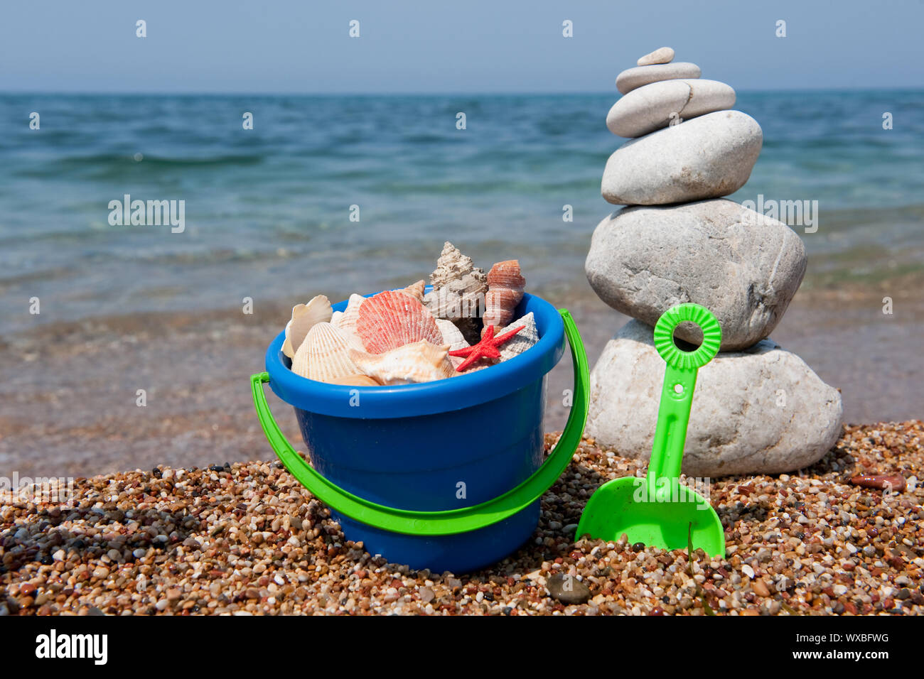 Shells on the beach in colorful bucket with stacked pebbles Stock Photo ...