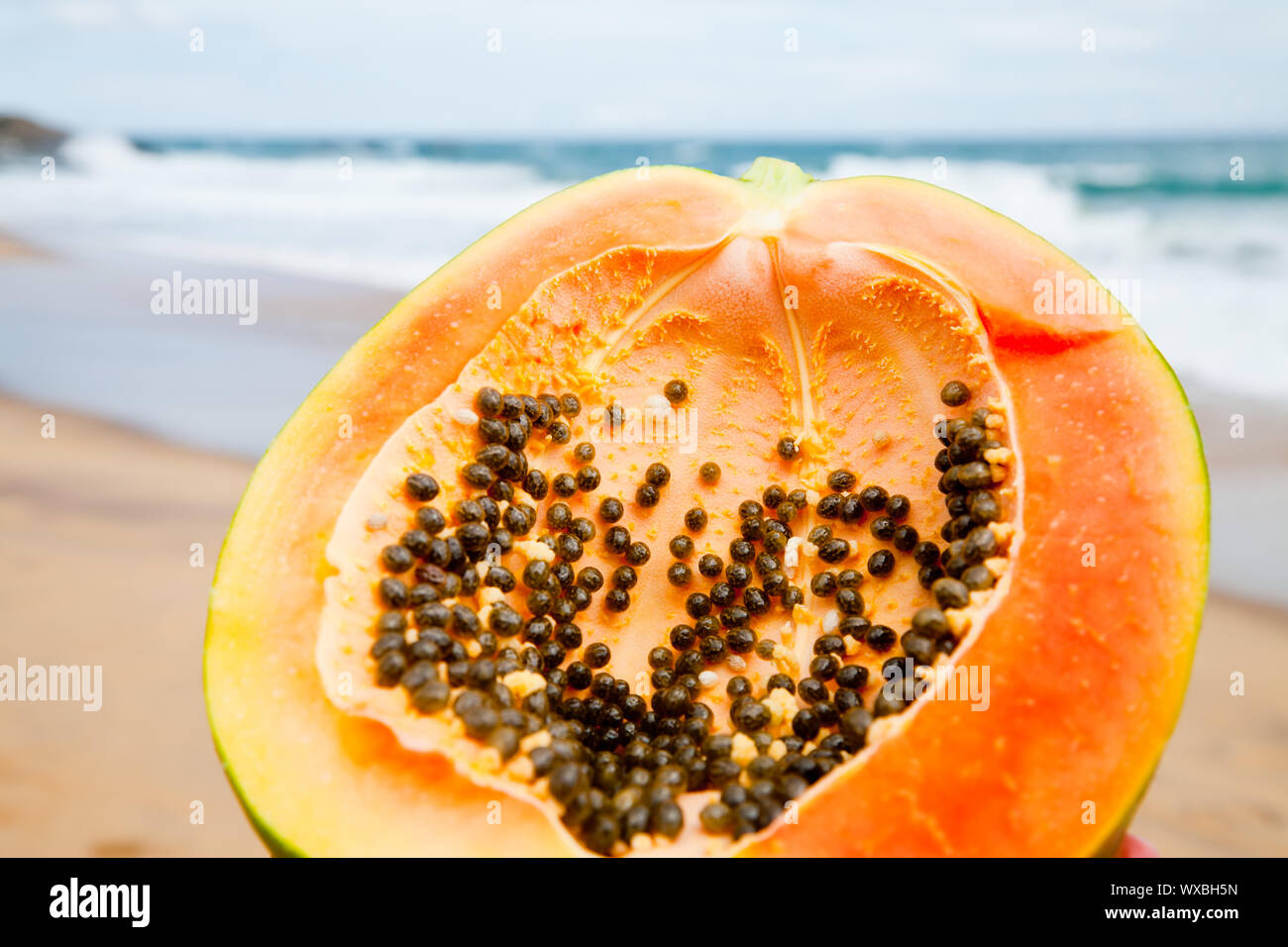 Ripe papaya cut in half on a beach Stock Photo - Alamy