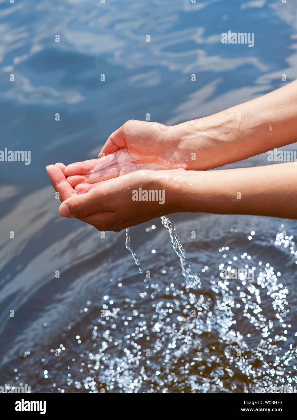 Water pouring out of a young woman's hands Stock Photo - Alamy