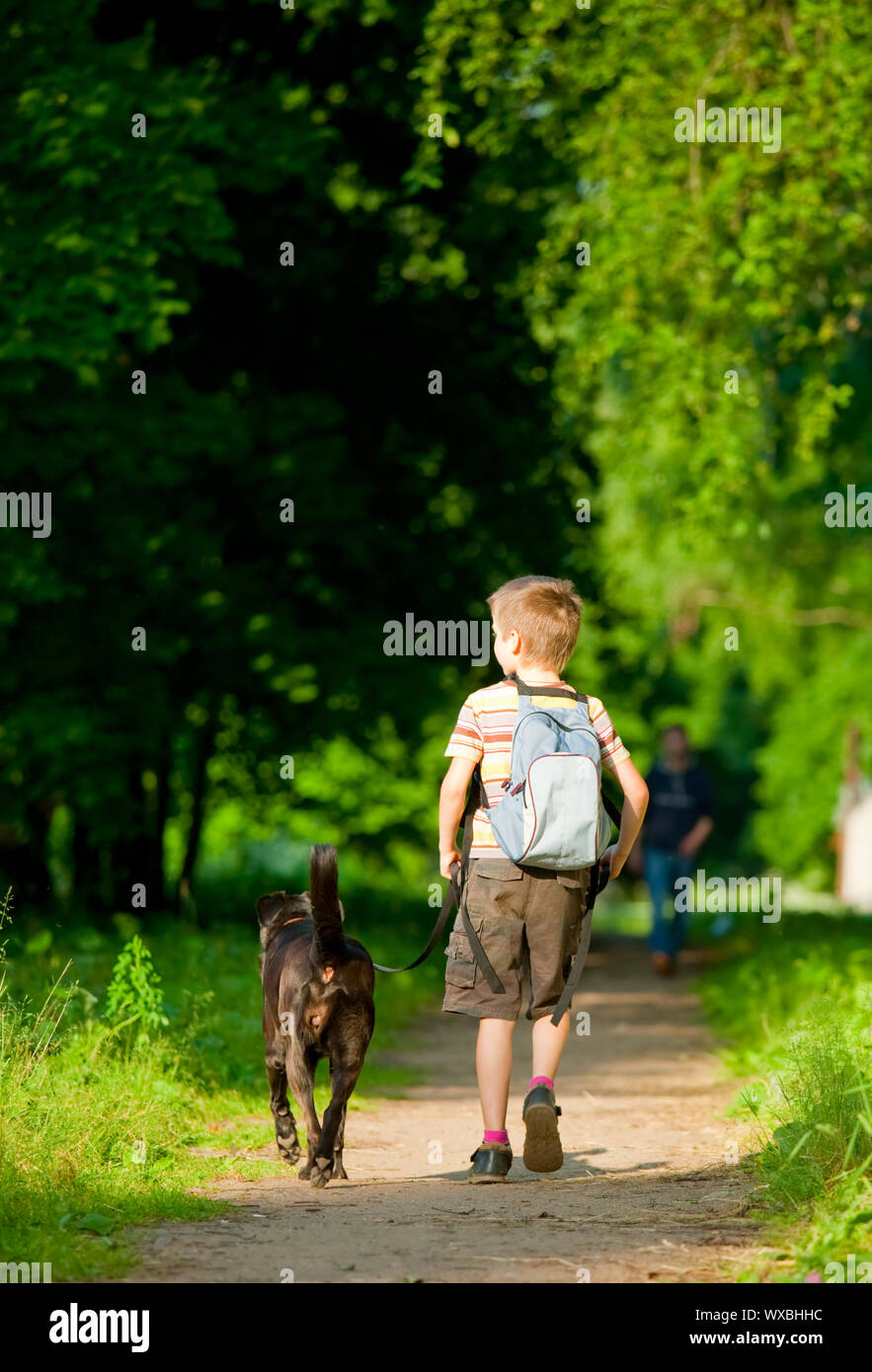 Young boy walking with black dog Stock Photo - Alamy