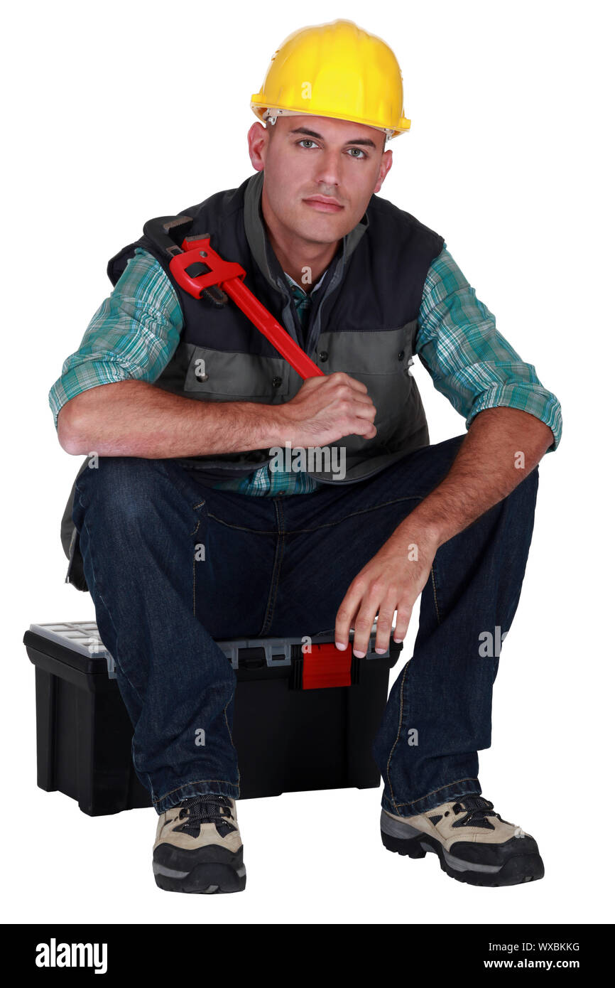 craftsman sitting on toolbox holding adjustable spanner Stock Photo - Alamy