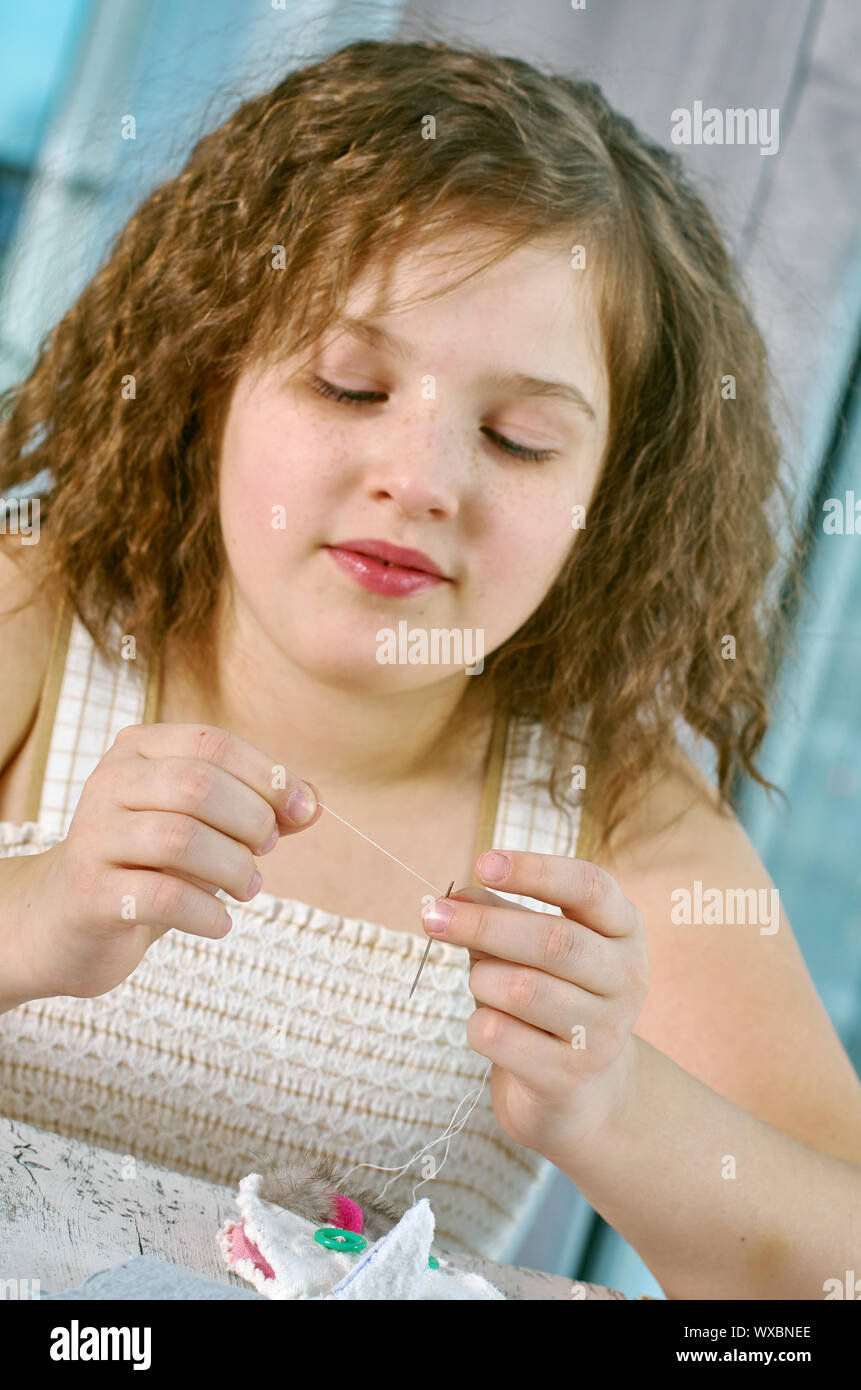 Little girl with a needle and thread Stock Photo - Alamy