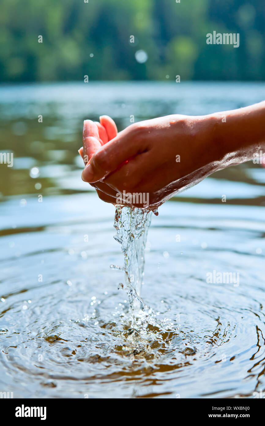 Water pouring out of a young woman's hands Stock Photo - Alamy