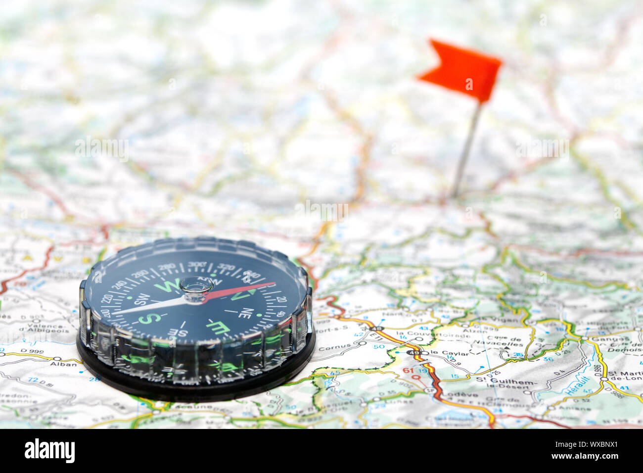 Compass on map with color flag pin in background Stock Photo - Alamy