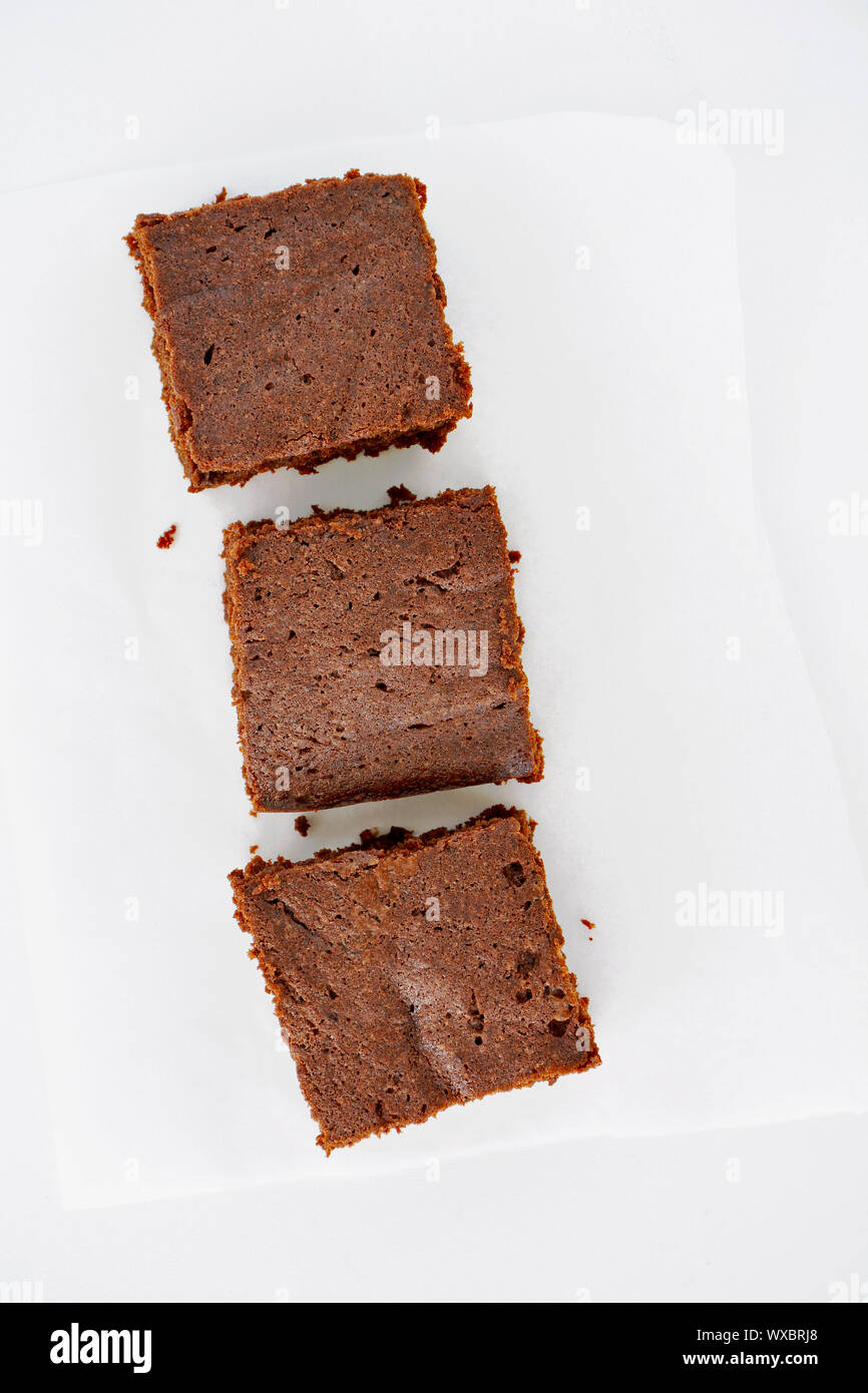 Homemade chocolate brownies squares on parchment on white background in ...