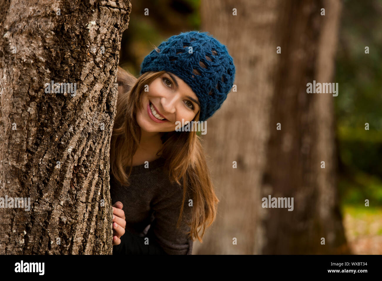 Happy woman hiding behind a tree in a beautiful autumn day Stock Photo ...