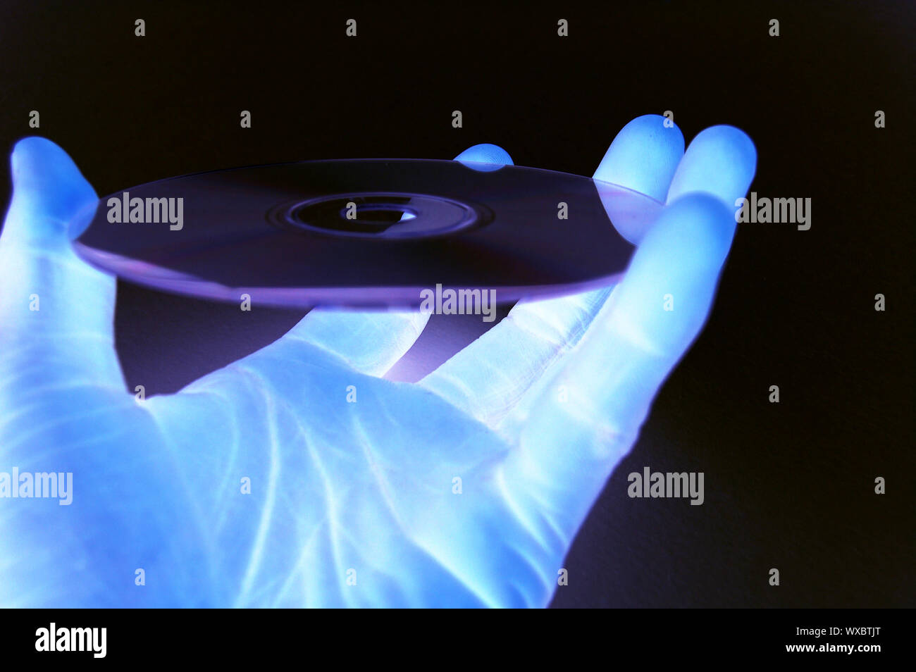 This is an image of a hand hold a data cd in a (dark technology room ...