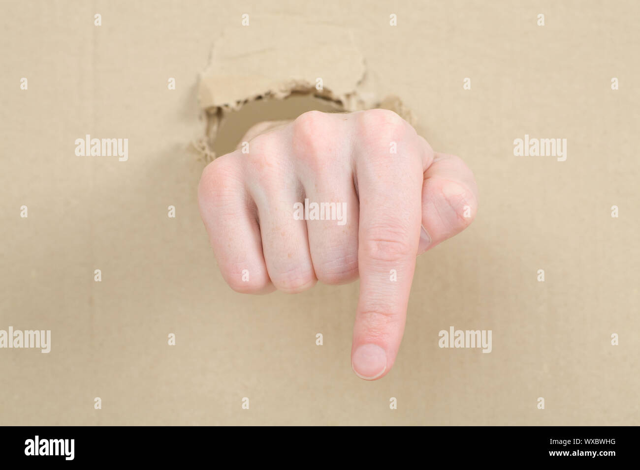 Gesture male hand through from hole in cardboard Stock Photo - Alamy