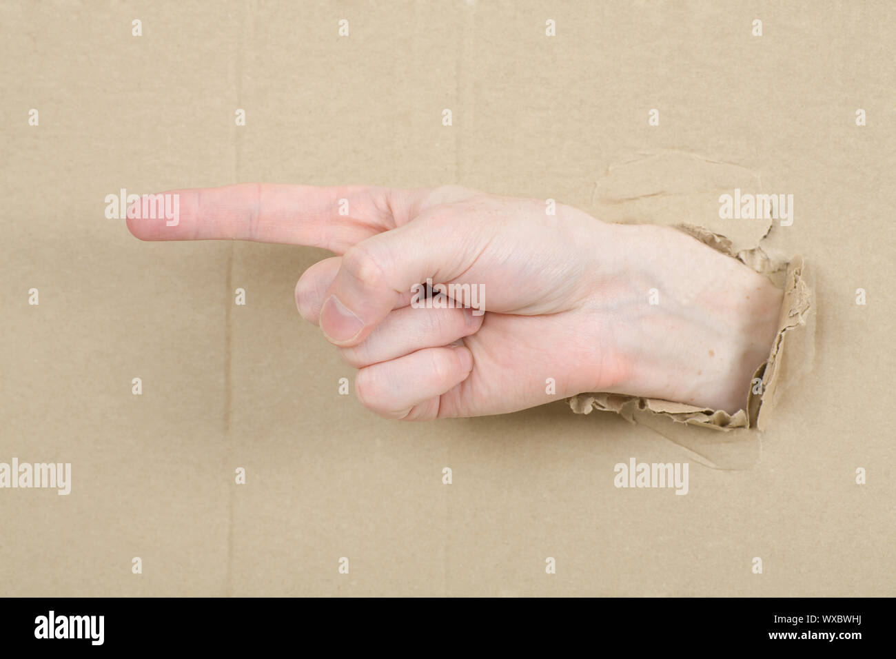 Gesture male hand through from hole in cardboard Stock Photo - Alamy