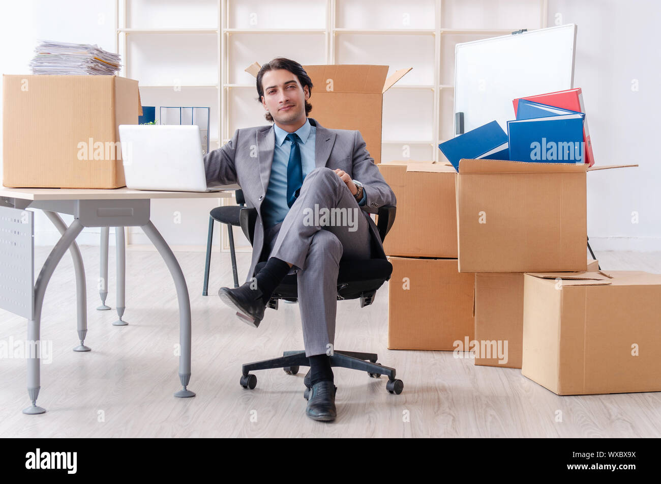 Young man employee with boxes in the office Stock Photo - Alamy