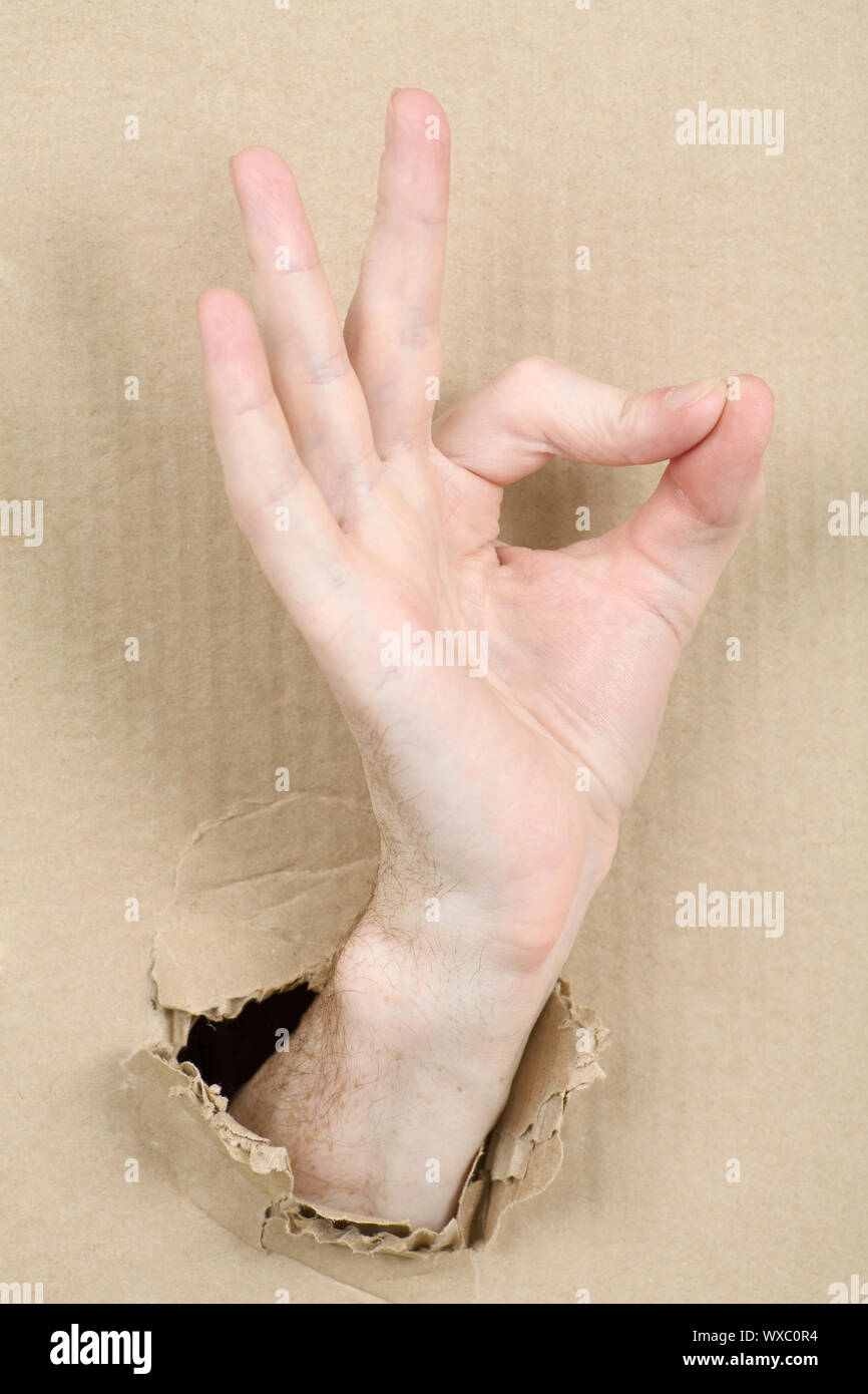 Gesture male hand through from hole in cardboard Stock Photo - Alamy