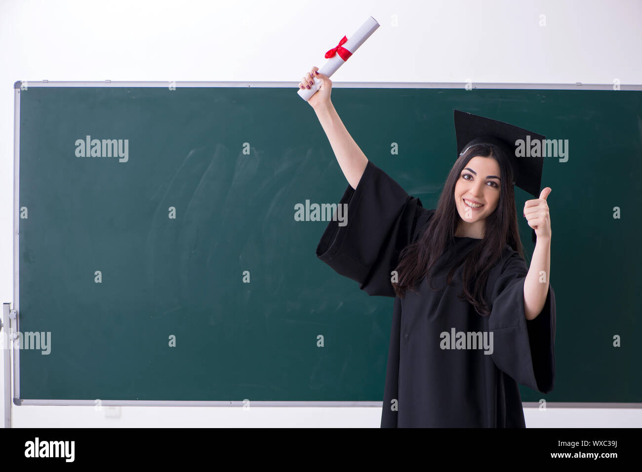 Female graduate student in front of green board Stock Photo - Alamy
