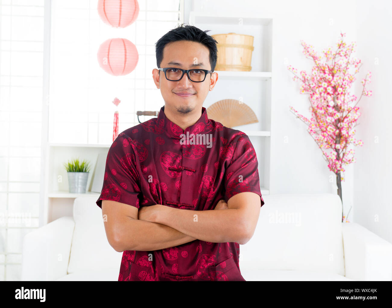 Chinese man in traditional Chinese Tang suit greeting standing indoors ...