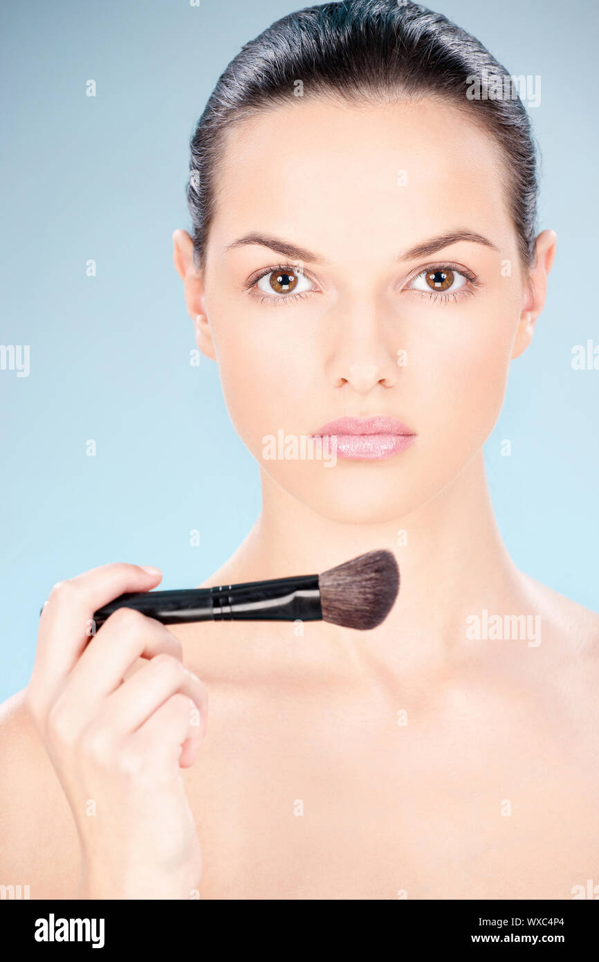 Portrait of a pretty young woman holding powder brush Stock Photo - Alamy