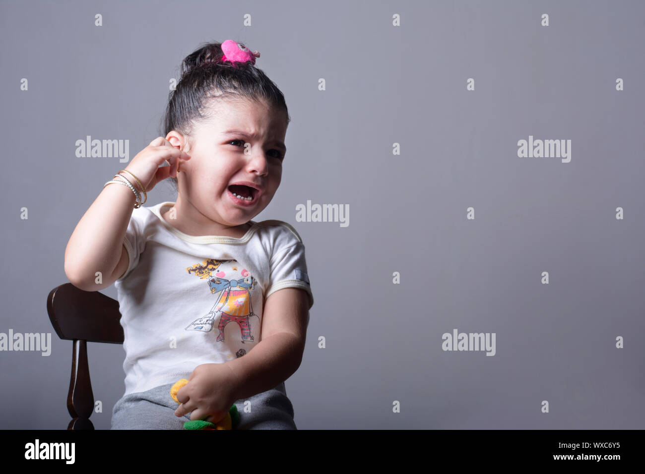 Lonely girl crying in front of gray background, pain or parent argument ...