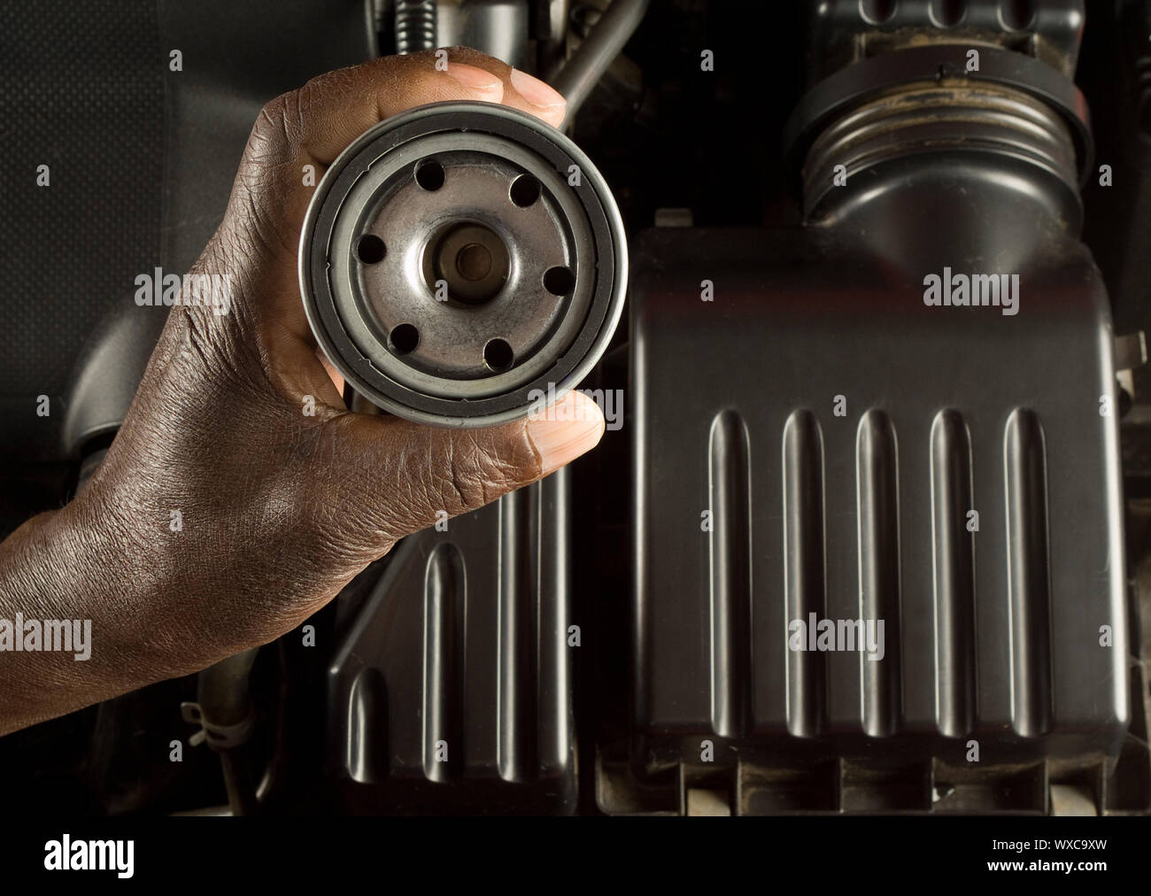 South African or American hand holding oil filter with modern car ...