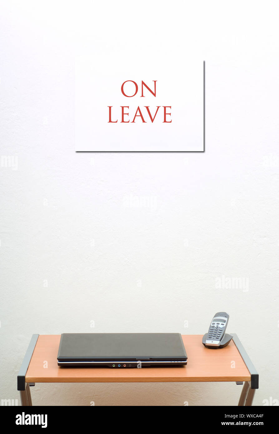 On leave sign on wall behind desk with laptop and portable phone Stock ...