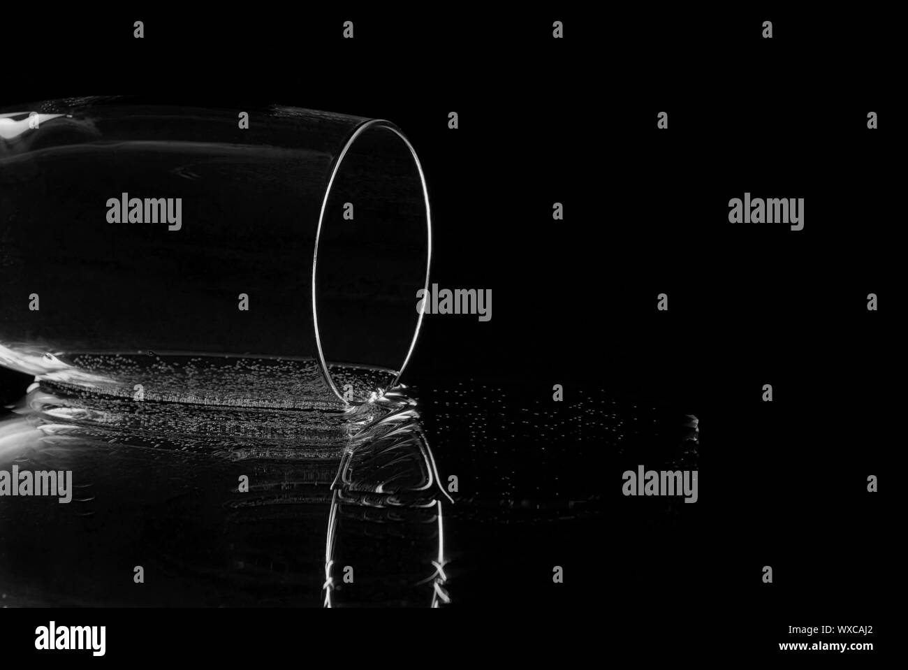 Empty champagne flute lying on it's side reflecting in a mirror with a ...