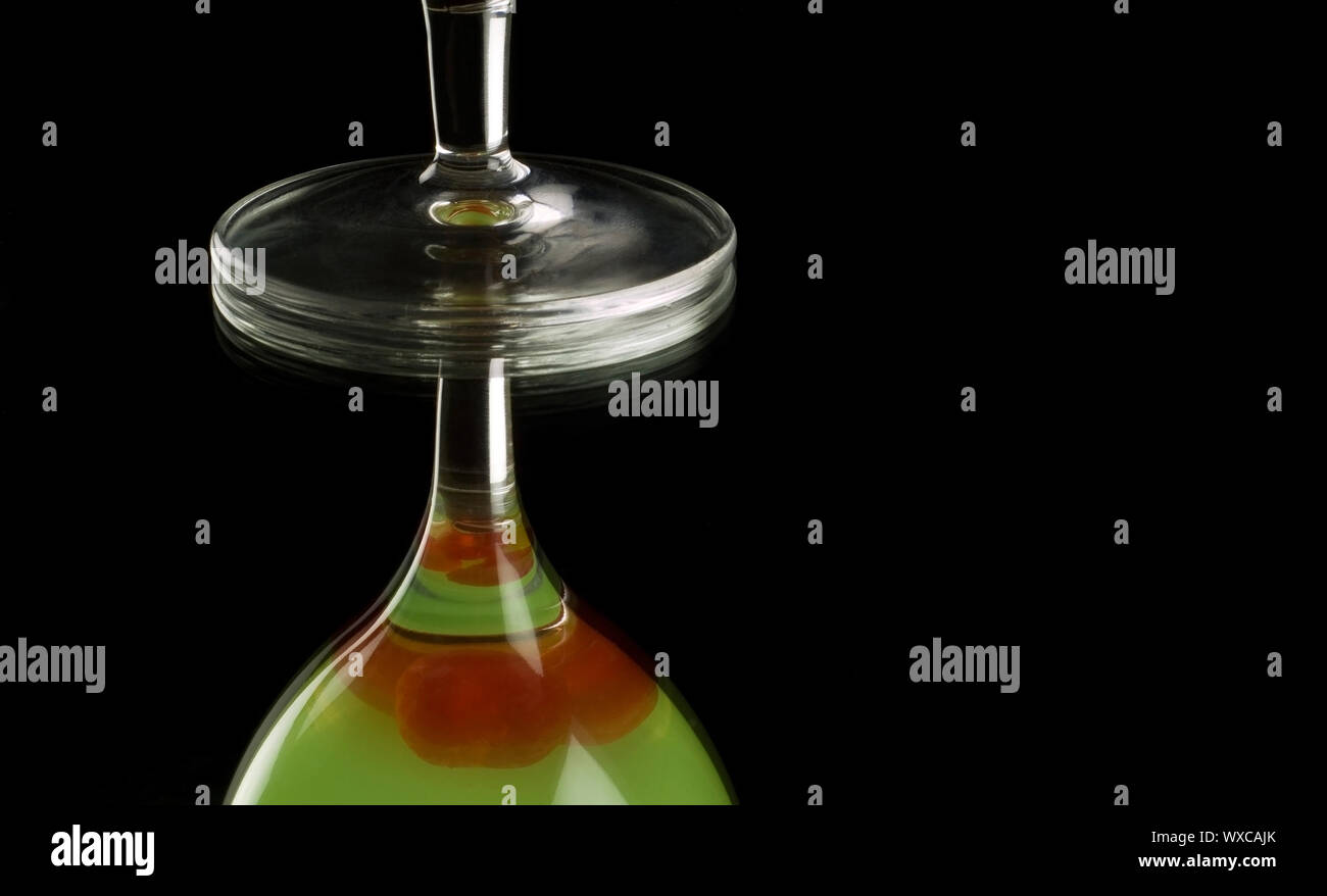 Brightly coloured cocktail drink with reflection and black background ...