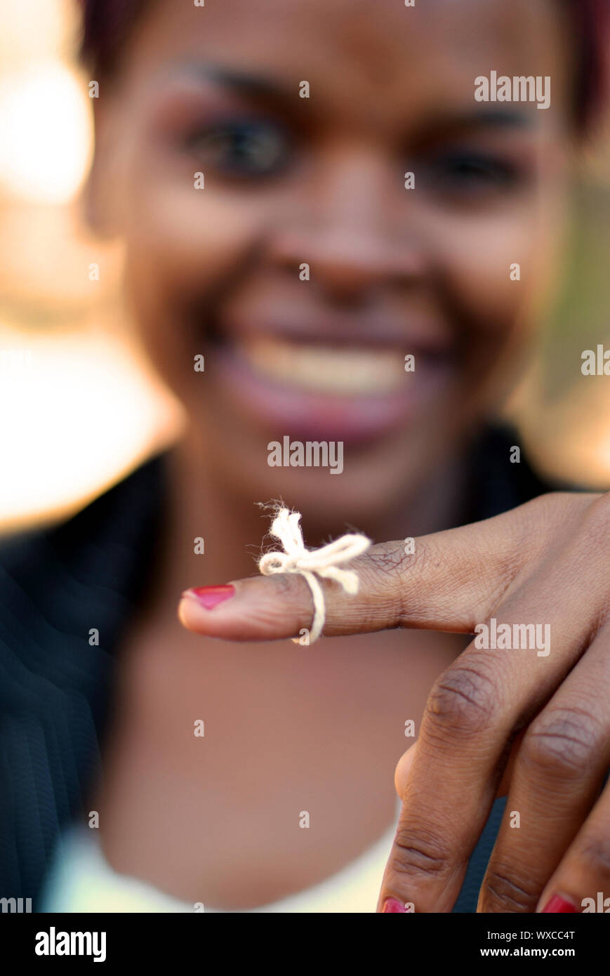 African American businesswoman with string tied to finger to remember ...