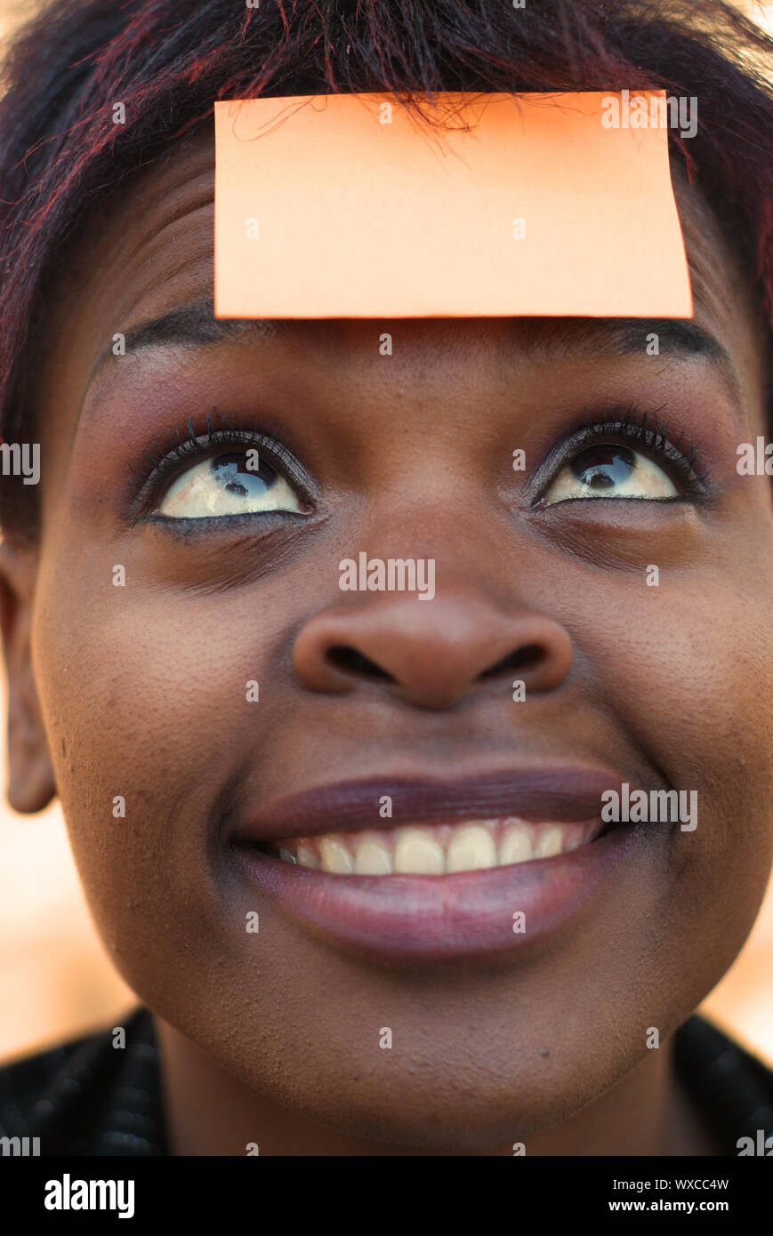 Smiling African American businesswoman with post it reminder note on ...