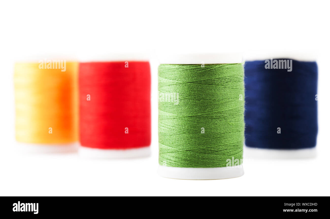 Four spools with green, yellow, blue and red thread Stock Photo - Alamy