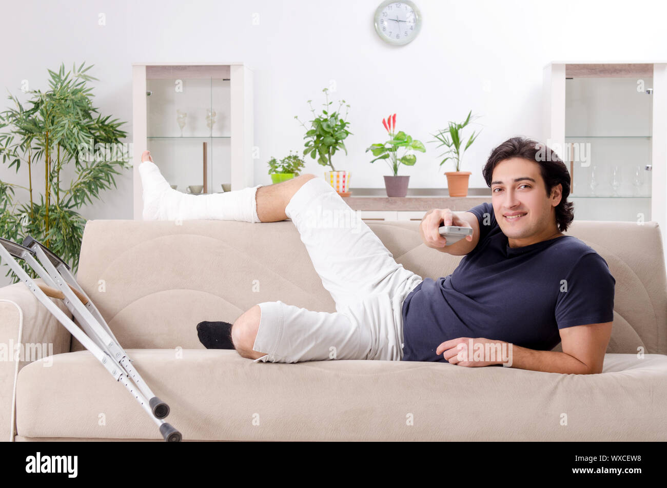Leg injured young man suffering at home Stock Photo - Alamy