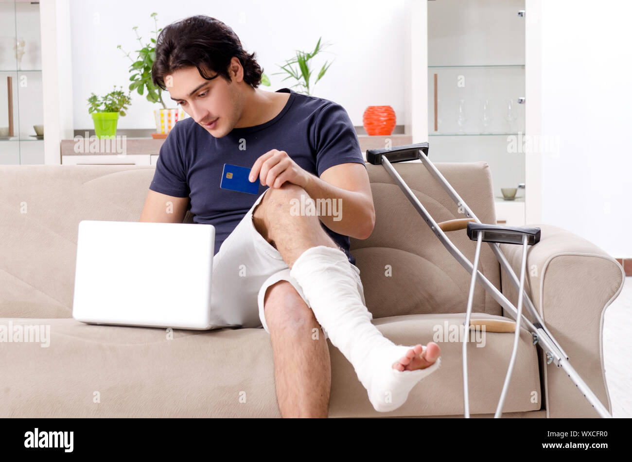 Leg injured young man suffering at home Stock Photo - Alamy