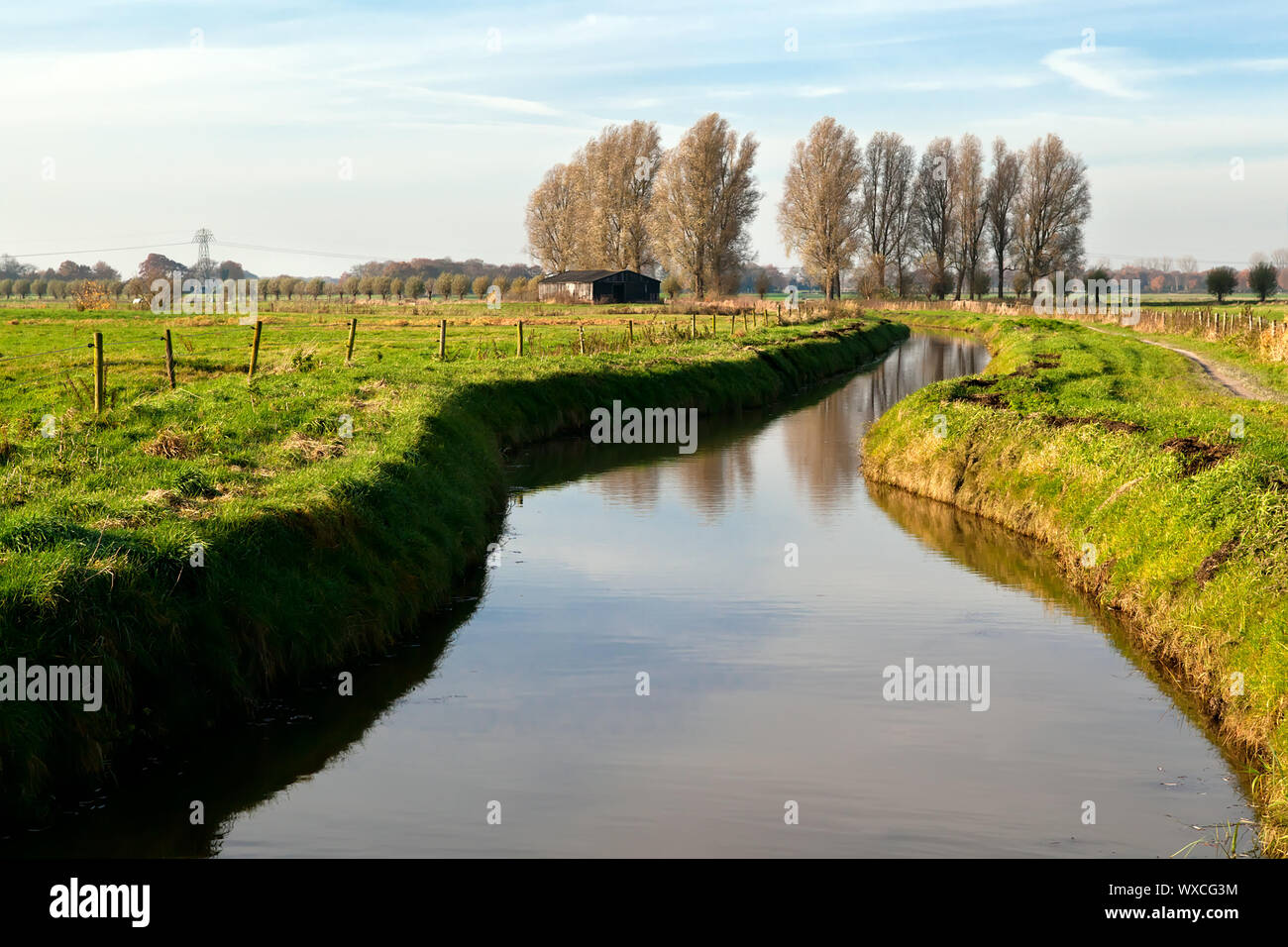curved canal by Dutch farmhouse and green pastures Stock Photo - Alamy