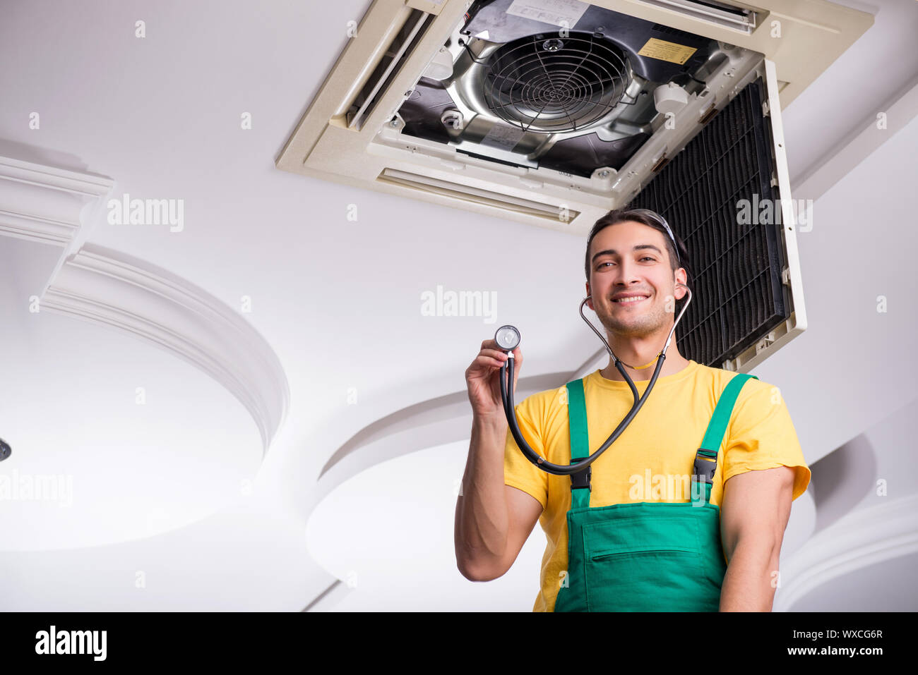 Young repairman repairing ceiling air conditioning unit Stock Photo - Alamy