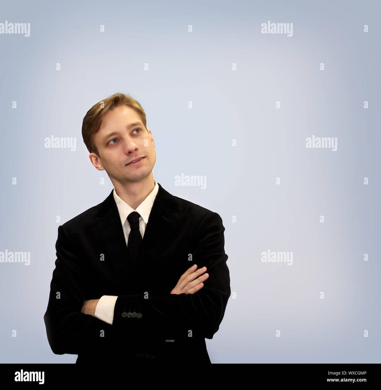 Young business in black suit looking upwards and thinking Stock Photo ...